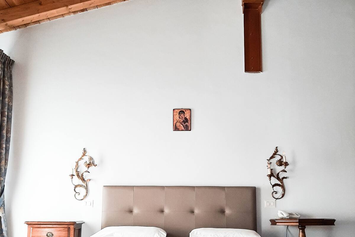 Quarto com uma cama grande, cabeceira de madeira, duas mesas de cabeceira e uma pequena decoração na parede.