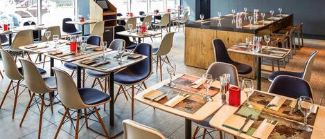 Um restaurante moderno com várias mesas, cadeiras e um bar.