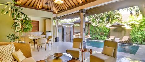 Uma sala de estar moderna com piscina, assentos confortáveis e cozinha.