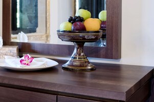 Uma tigela de frutas sobre uma mesa de madeira, com um espelho refletindo o ambiente.