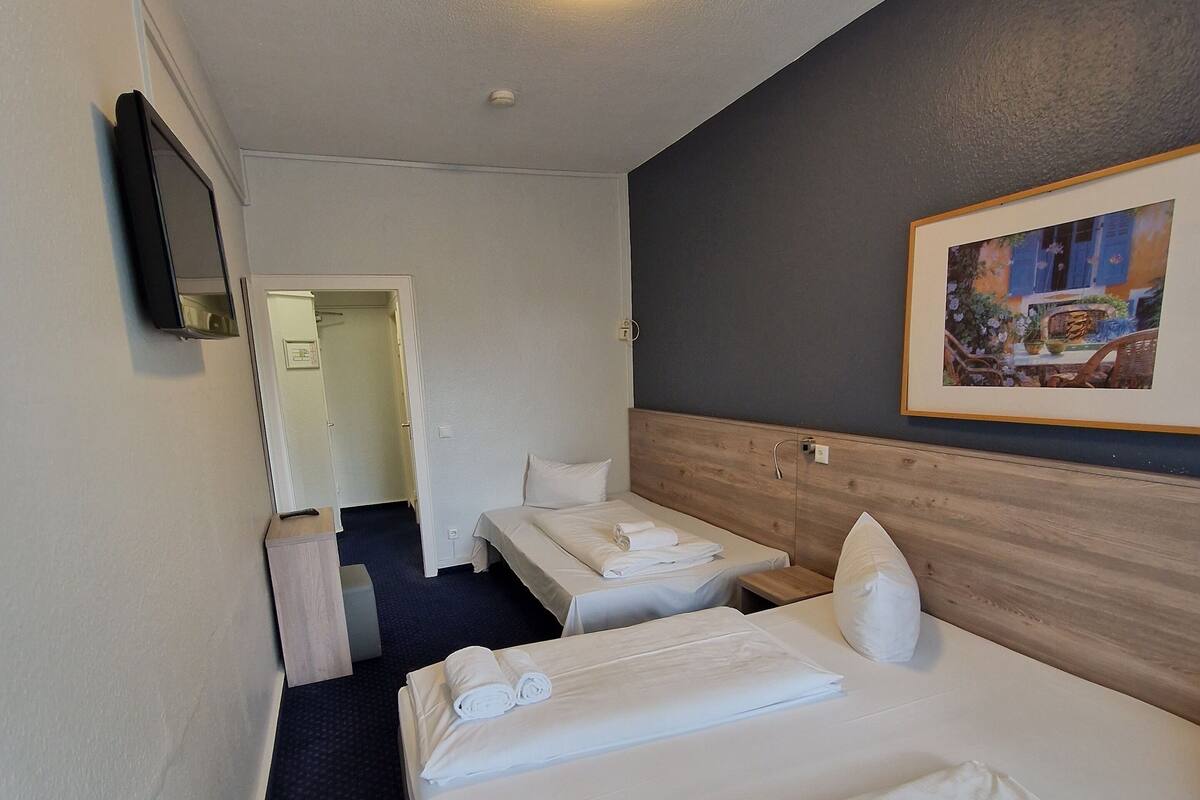 Quarto de hotel com duas camas, televisão de tela plana na parede e um quadro emoldurado na parede.