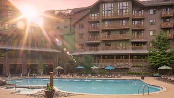 Um hotel com piscina, área de estar externa e vista para o pôr do sol.