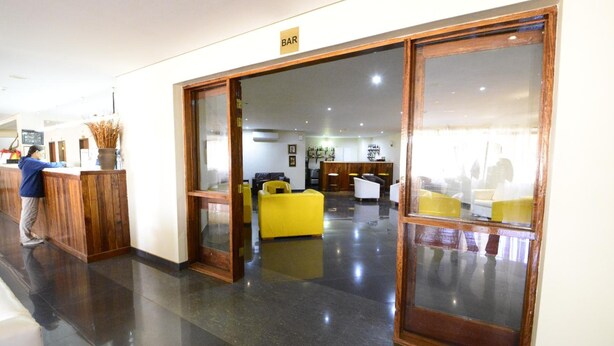 Um hall de hotel com balcão de recepção, um sofá amarelo e área de bar.
