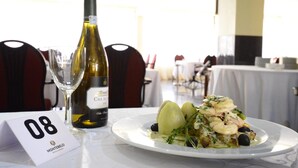 Uma mesa de jantar com uma garrafa de vinho, um copo e um prato de comida.