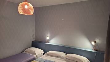 Quarto com cama, cabeceira e luminária pendente.