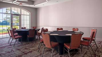 Uma sala de conferências com uma mesa grande e cadeiras, janelas amplas e piso coberto por carpete.