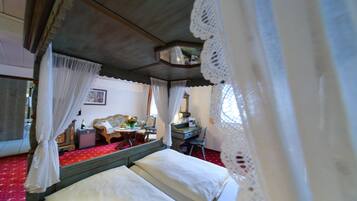 Quarto com cama, escrivaninha e cadeira. Há uma janela com cortinas.