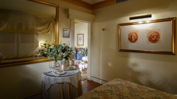 Um quarto com uma mesa de jantar posta para dois, um vaso com flores e uma obra de arte emoldurada na parede.