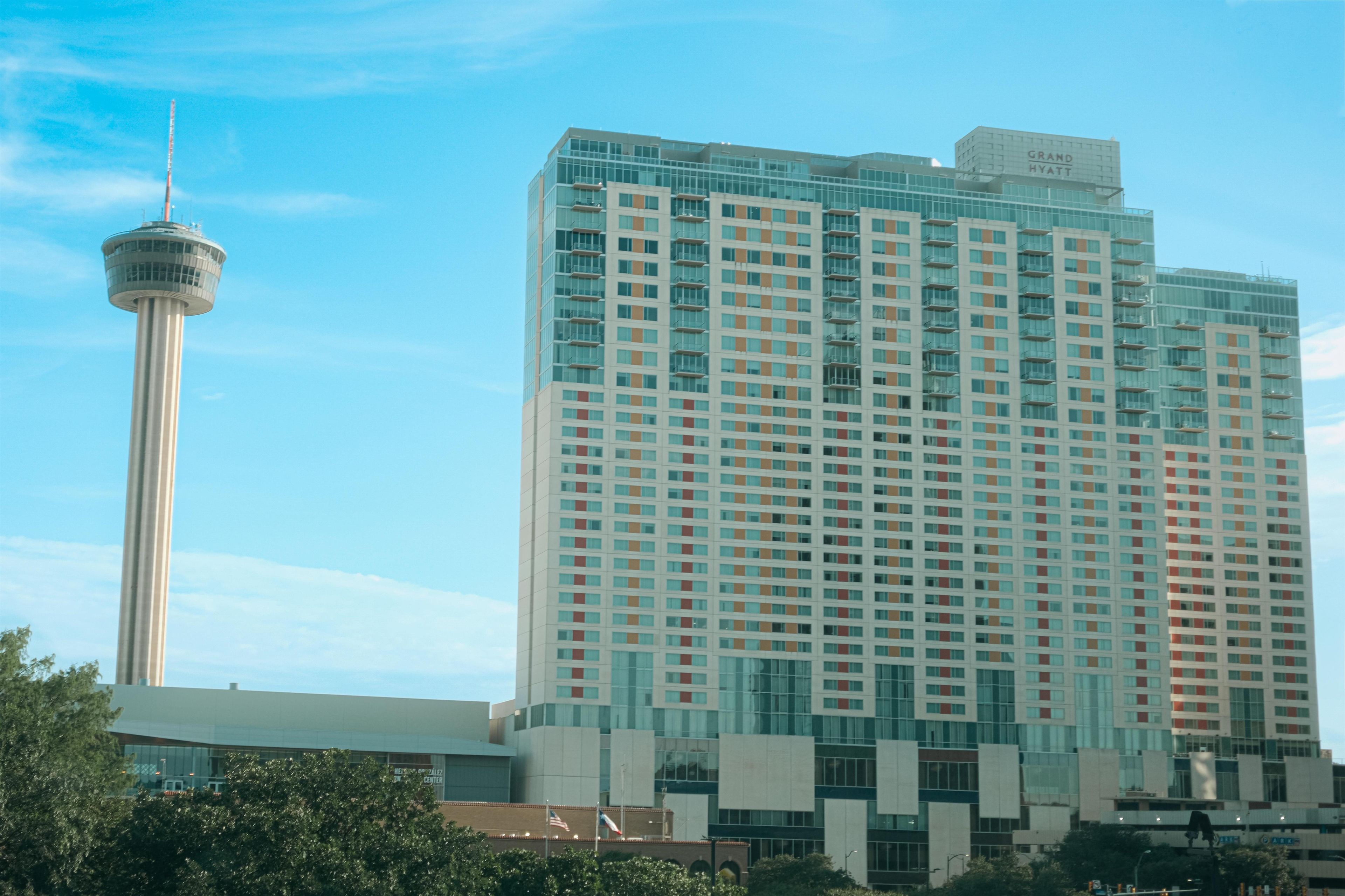 Um hotel moderno com muitos andares e uma fachada de vidro, destacando-se por uma torre imponente.