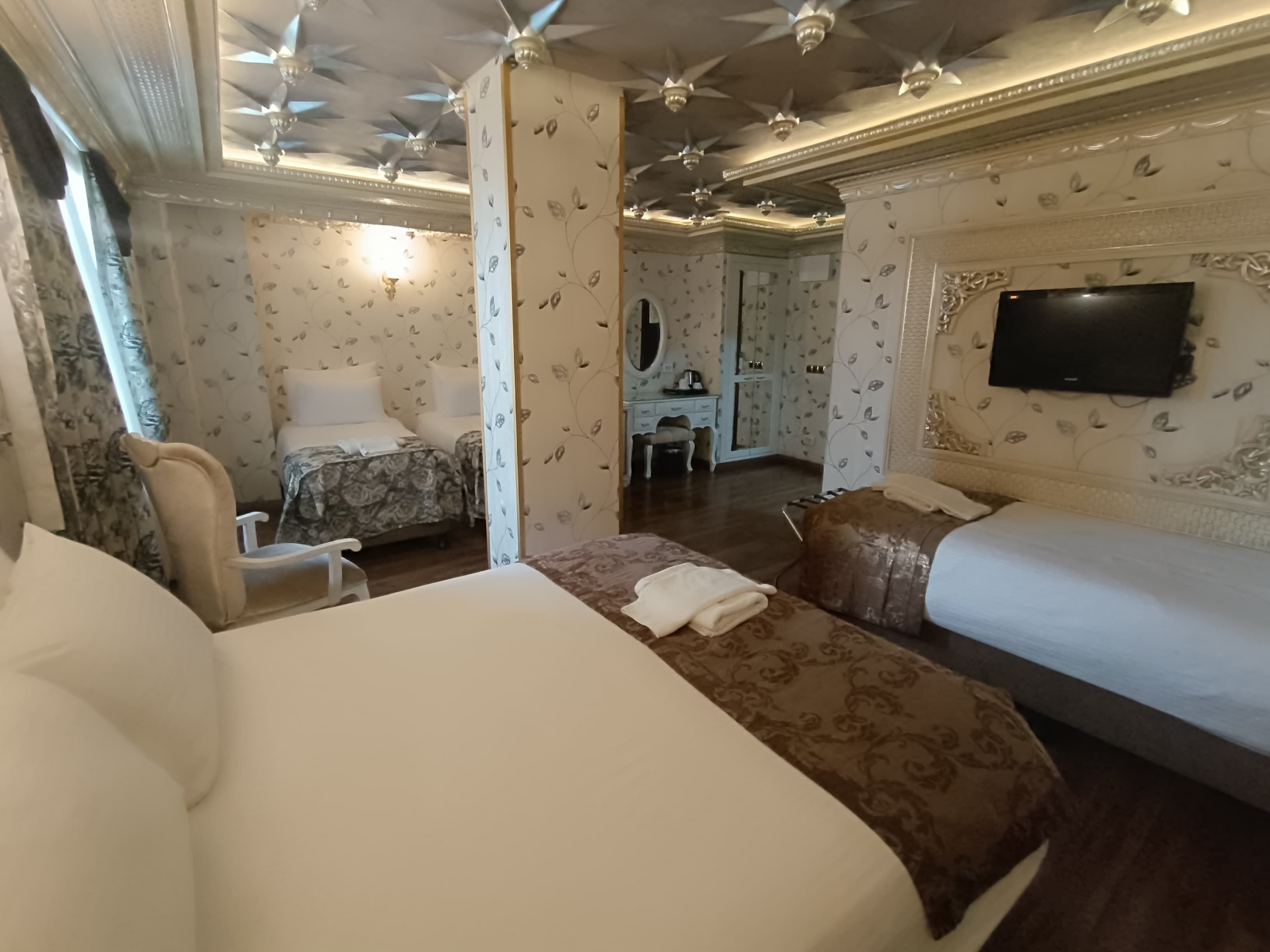 Quarto de hotel com uma cama grande, um sofá, uma mesa e uma televisão.