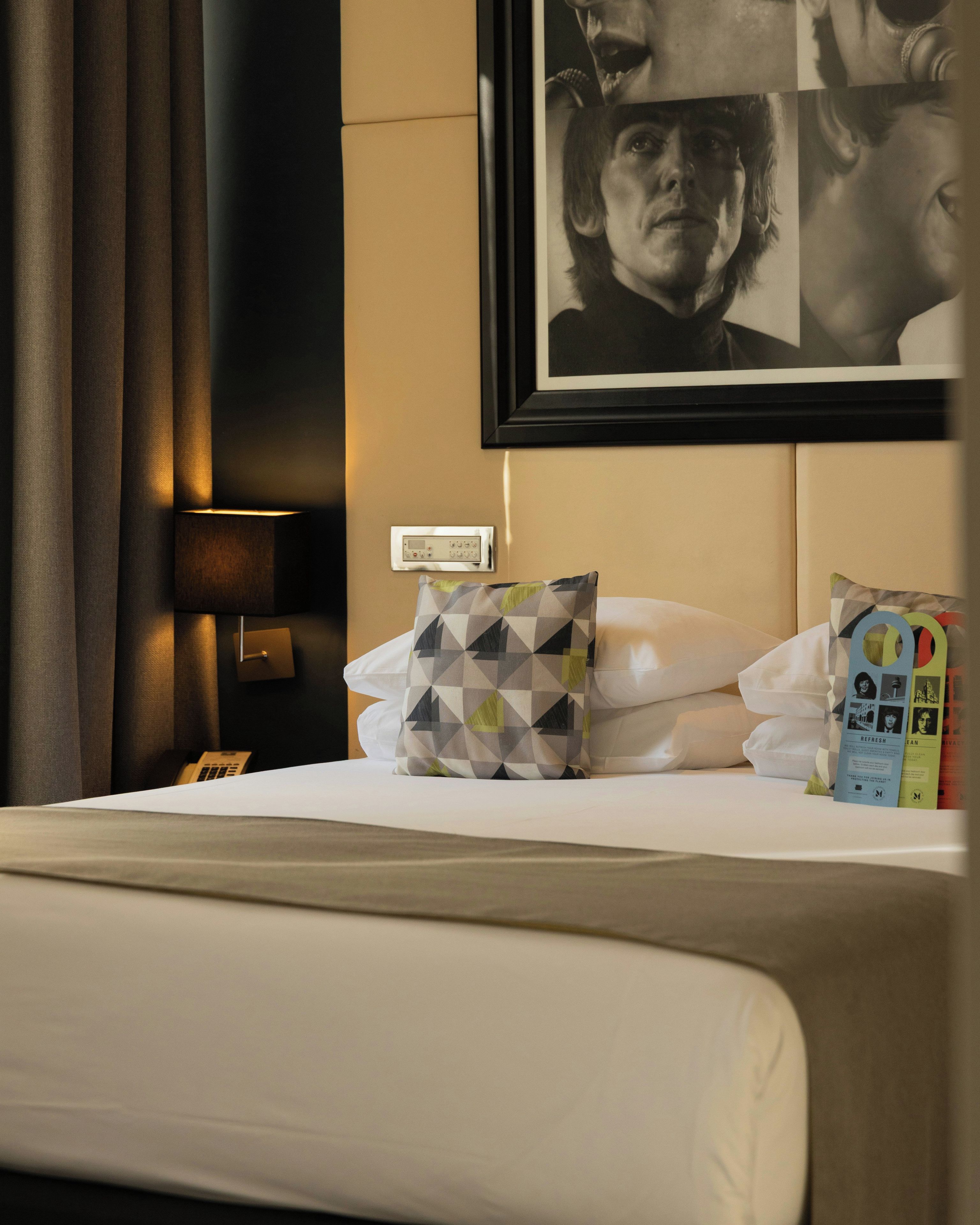 Quarto de hotel com cama, almofadas, relógio de parede e quadro emoldurado.