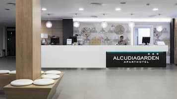 Uma área de recepção com design moderno, com um balcão de atendimento, um pilar de madeira e um espaço de estar com banquetas redondas.