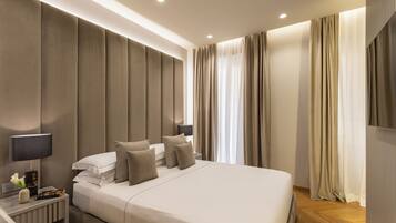 Quarto de hotel moderno com uma cama grande, mesas de cabeceira, luminária e cortinas.
