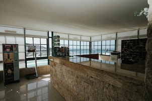 Um interior moderno com bancada de pedra, grandes janelas com vista para o mar e uma máquina de venda automática.