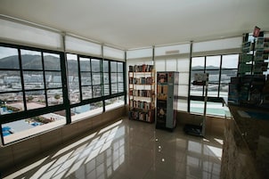 Quarto espaçoso com grandes janelas, uma estante de livros e uma máquina de vendas.