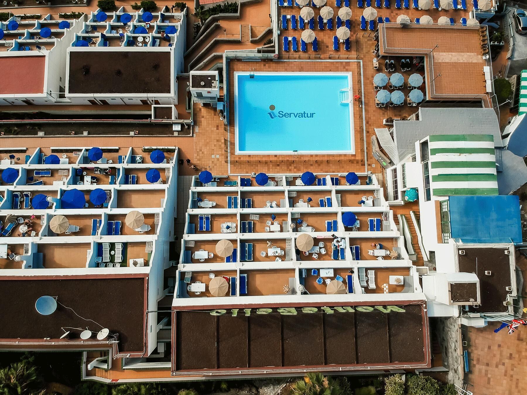 Um hotel com várias varandas, piscina central e áreas de estar ao ar livre.