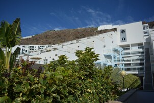 Um edifício moderno com várias varandas e um cenário de colina.