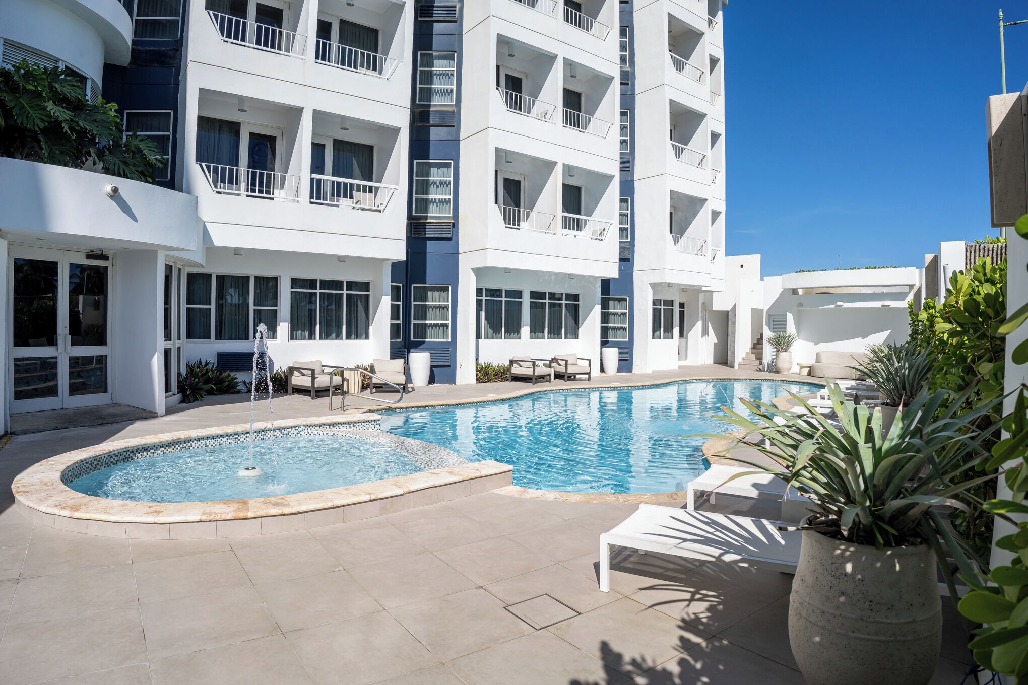 Um hotel moderno com piscina, área de estar ao ar livre e varandas.