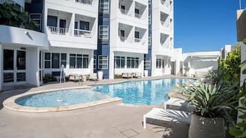 Um hotel moderno com piscina, área de estar ao ar livre e varandas.
