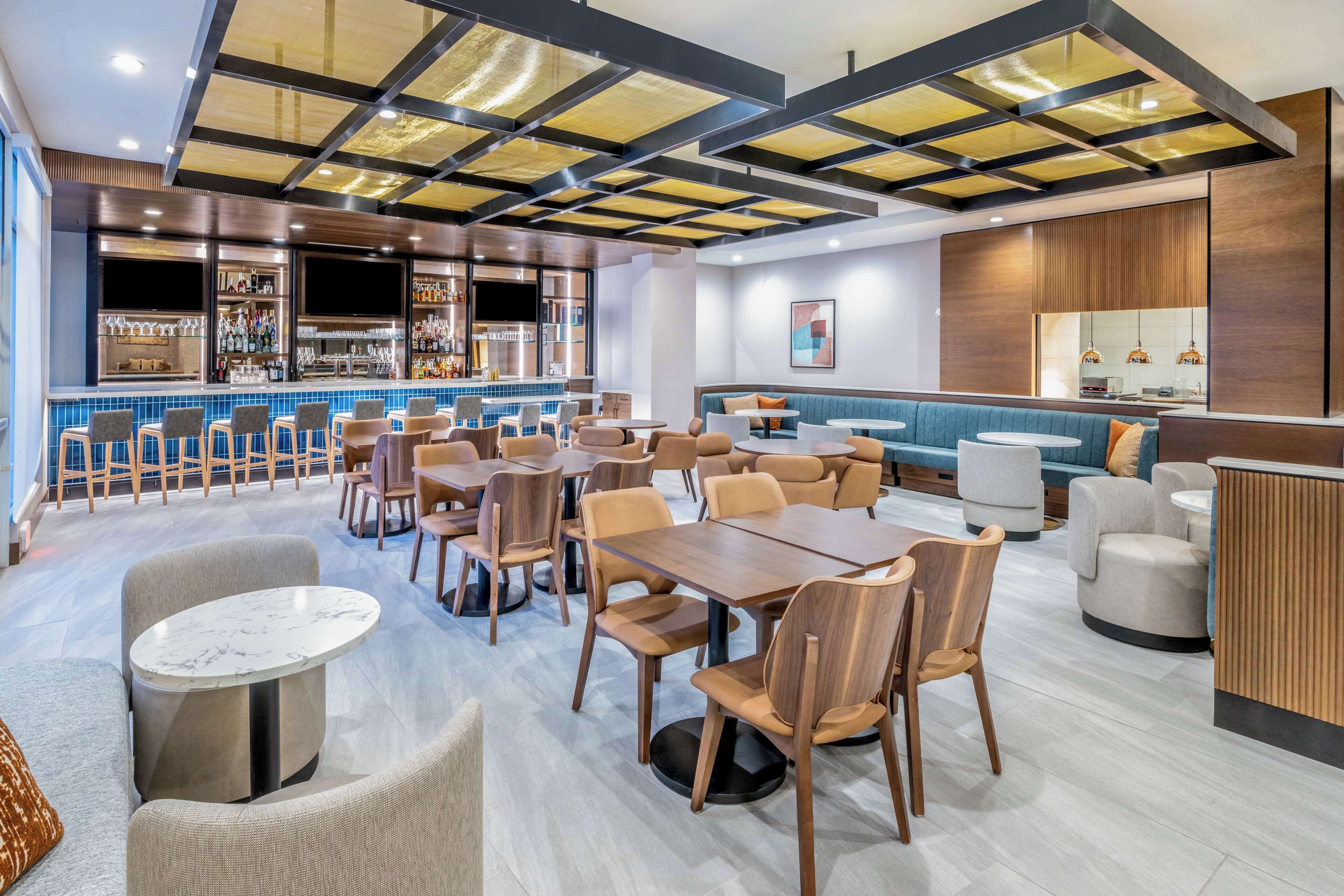 Um restaurante moderno com área de bar, diferentes opções de assentos e um balcão.