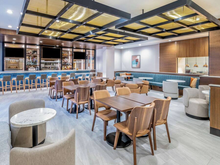 Um restaurante moderno com área de bar, diferentes opções de assentos e um balcão.
