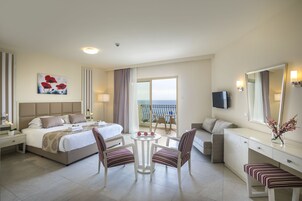 Quarto de hotel com cama, escrivaninha, cadeira, mesa pequena e varanda com vista.