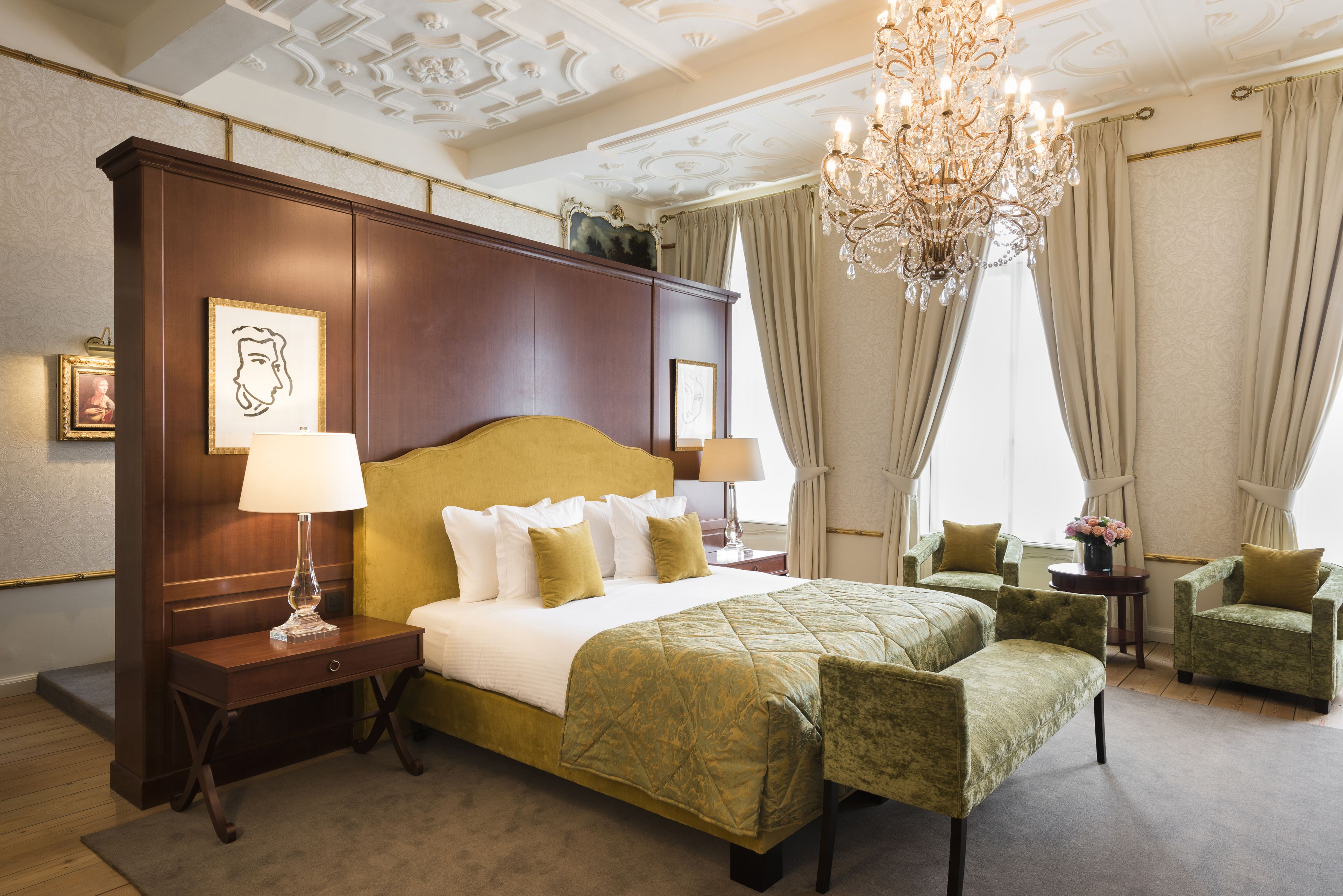 Quarto de hotel espaçoso com cama grande, lustre e vista da cidade.