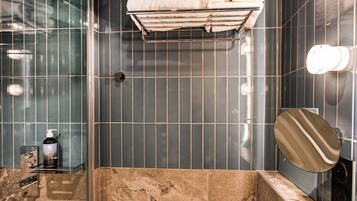 Casa de banho com cabine de duche em vidro, lavatório de mármore e toalheiro com toalhas dobradas.