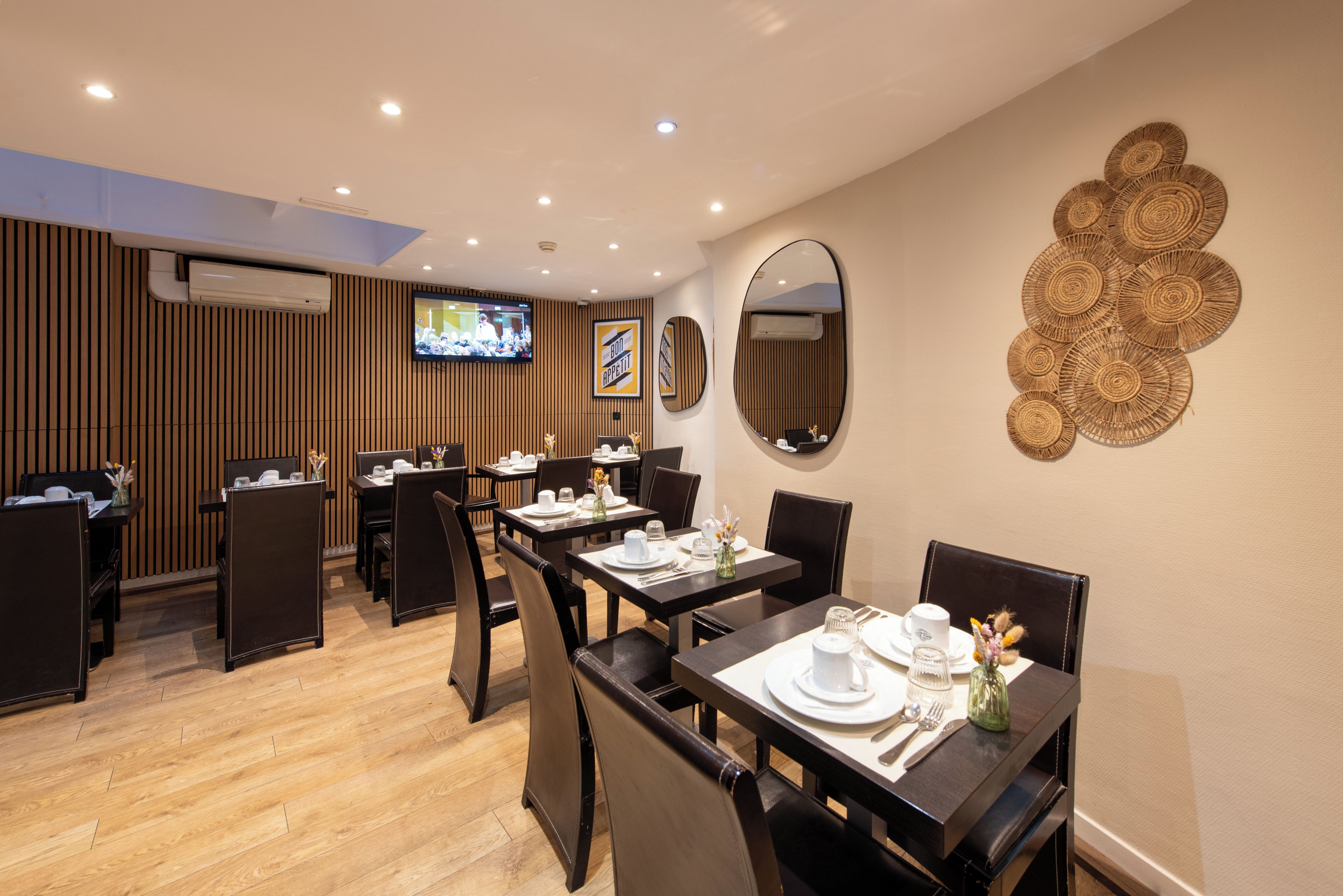 Restaurante com paredes revestidas de madeira, televisão montada na parede e um objeto decorativo.
