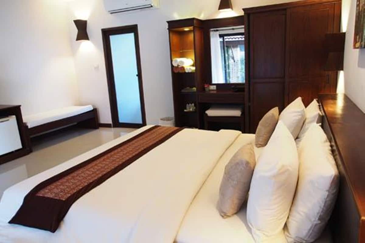 Quarto de hotel com uma cama grande, mesa de cabeceira, guarda-roupa e espelho.