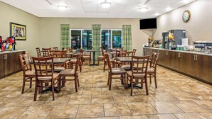 Um restaurante com várias mesas e cadeiras, um balcão com uma máquina de café e um relógio na parede.