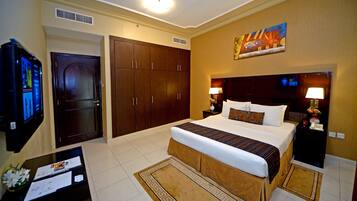 Quarto de hotel com uma cama grande, duas mesas de cabeceira com luminárias, uma TV de tela plana, um guarda-roupa de madeira e um quadro na parede.