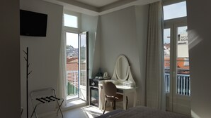 Quarto de hotel com cama, secretária com cadeira, espelho e televisão na parede.