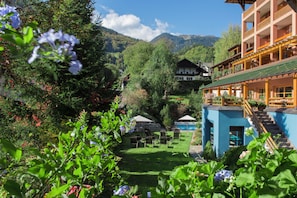 Um hotel com piscina, área de estar externa e montanhas ao fundo.