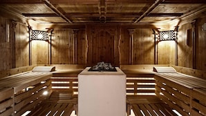 Sala de sauna com bancos de madeira e elemento central de pedra, provavelmente para aquecimento.