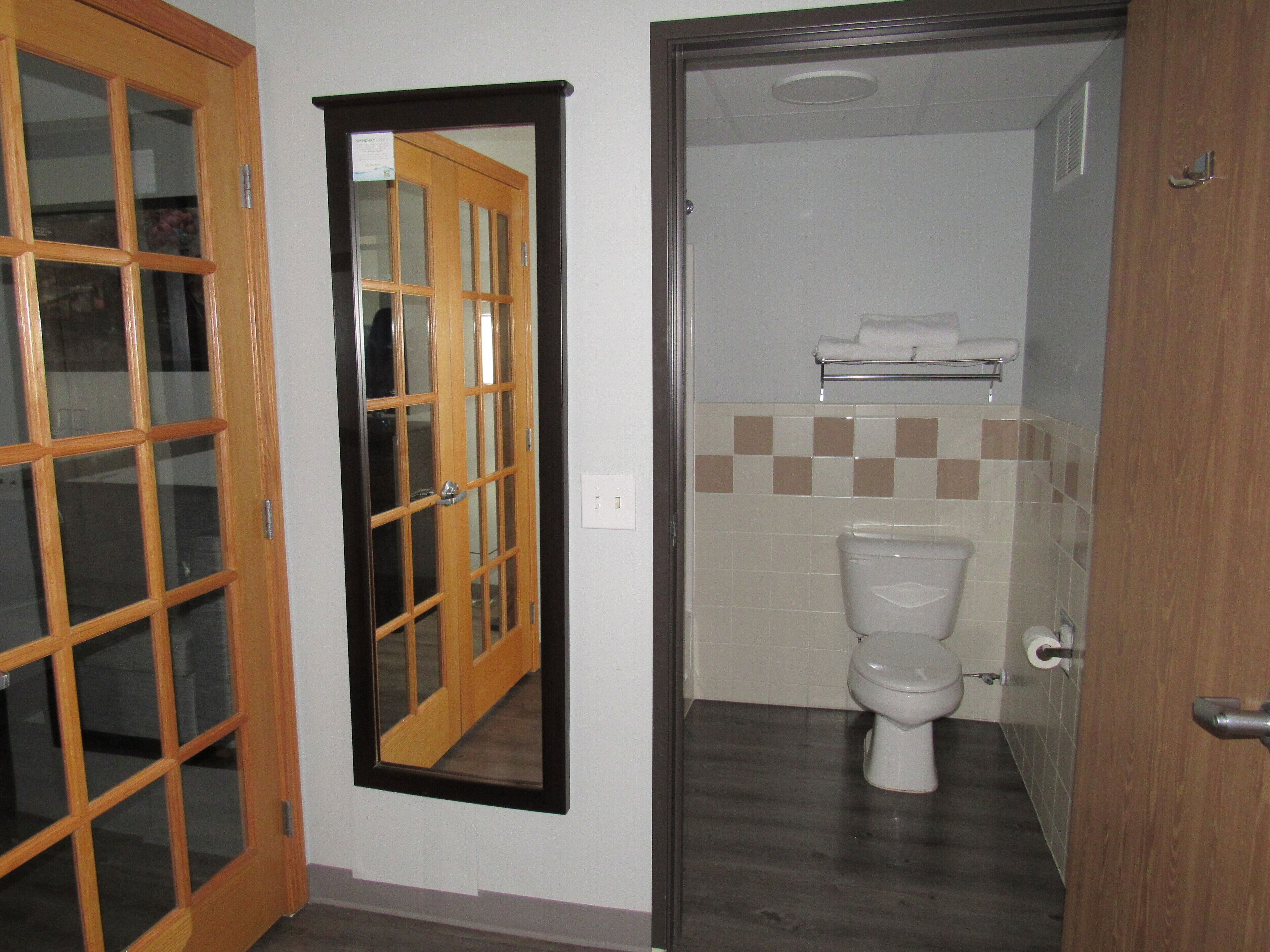 Uma casa de banho com sanita, porta-toalhas e espelho.