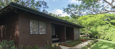 Uma casa de dois andares com varanda da frente, alpendre coberto e um jardim bem cuidado.