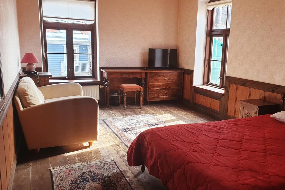 Quarto com cama, escrivaninha, cadeira e janela.