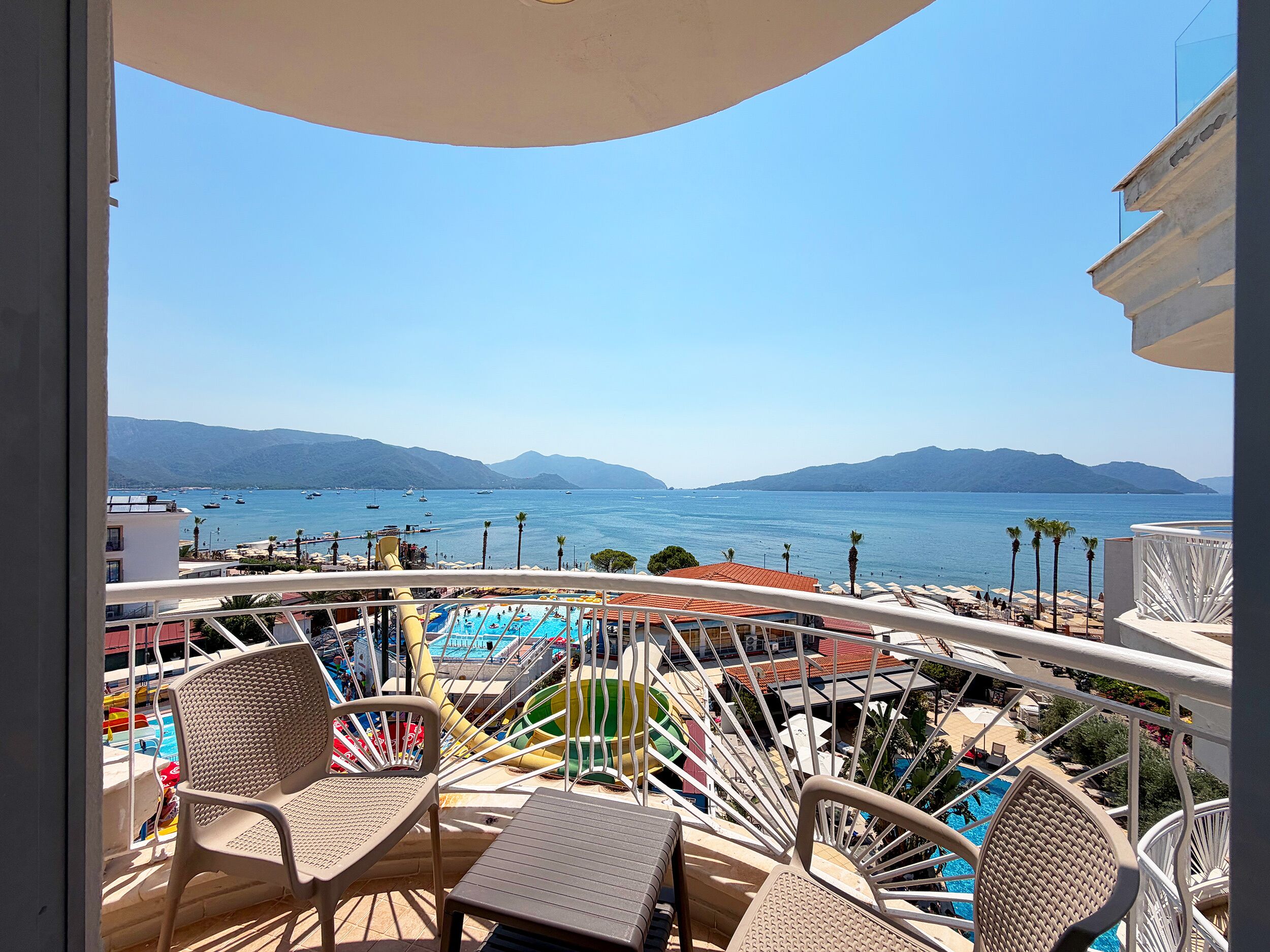Uma varanda com vista para o mar, uma piscina e uma cadeira.
