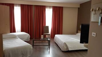 Quarto de hotel com duas camas, uma mesinha, uma cadeira e uma televisão.