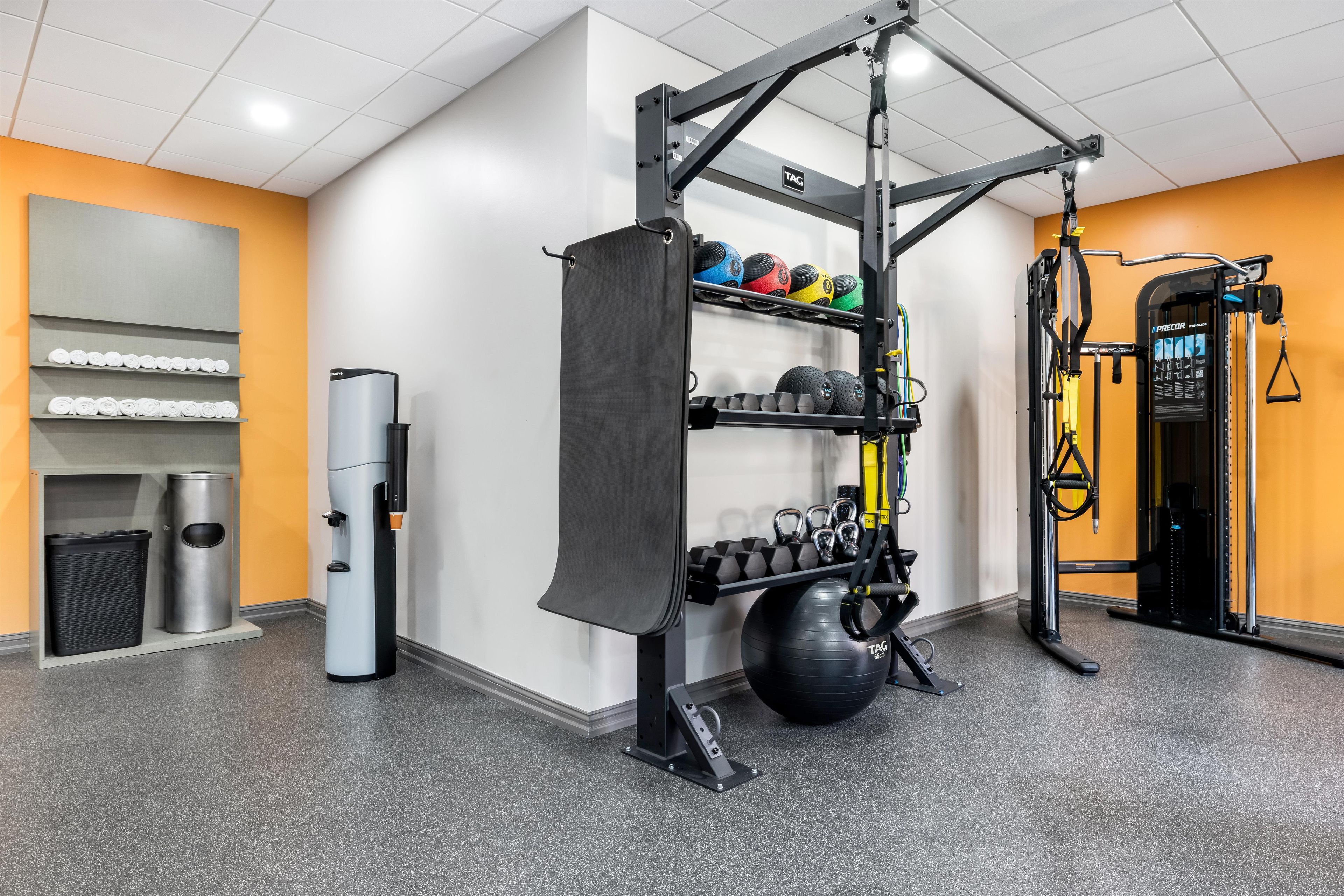 Uma academia com barra de puxada, kettlebells e suporte para agachamento.