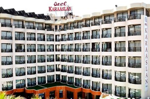 Um hotel de vários andares com varandas, aparelhos de ar condicionado e uma placa com a inscrição 'Hotel Karaasian'.