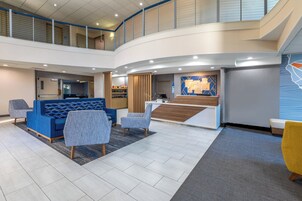 Um lobby moderno com balcão de recepção, área de estar e escadaria.