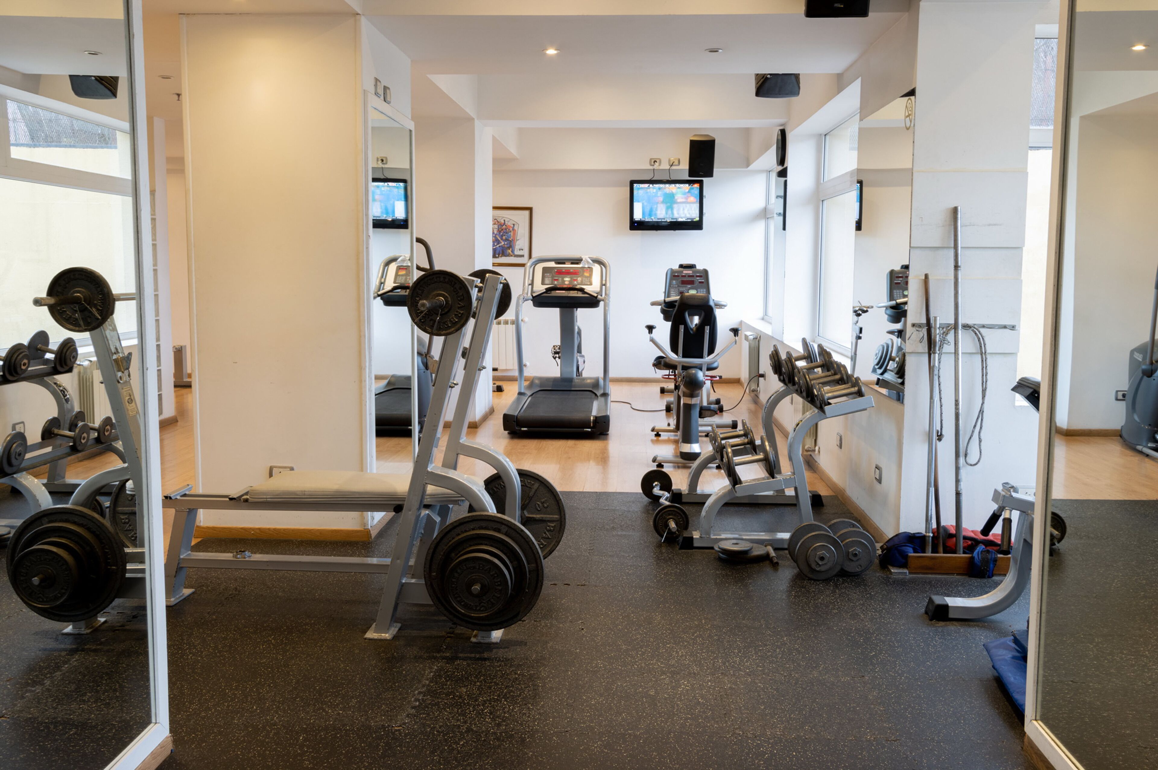 Uma academia com diversos equipamentos de exercícios, incluindo esteiras, aparelhos de musculação e pesos livres.