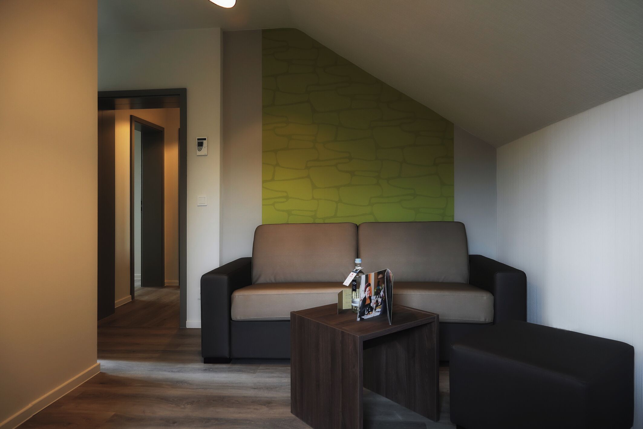 Uma sala de estar moderna com um sofá, uma mesa de centro e uma escada com uma parede verde decorativa.