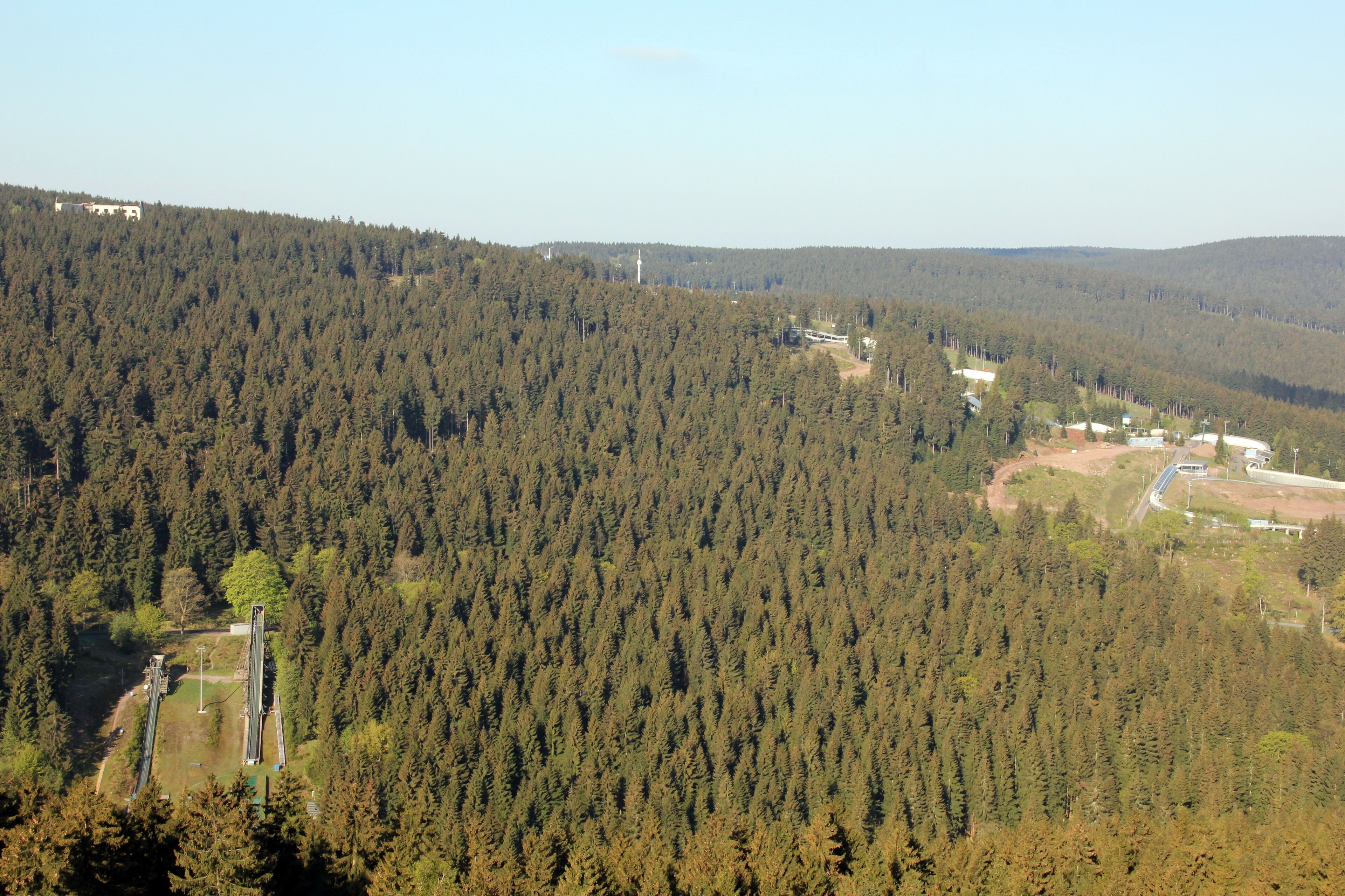 Uma área montanhosa coberta por floresta, com um pequeno edifício e uma estrada.