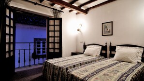 Quarto com duas camas, mesa de cabeceira, luminária na parede e um quadro emoldurado.