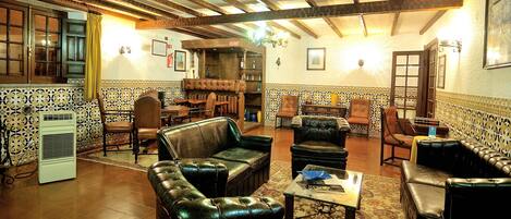 Um hall amplo com sofás de couro, uma mesa de centro e um bar com bancos.