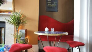 Uma área de estar acolhedora com uma mesa redonda, duas cadeiras vermelhas e um vaso de planta.