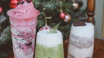 Três bebidas dispostas em camadas sobre uma mesa de madeira, com uma árvore de Natal ao fundo.